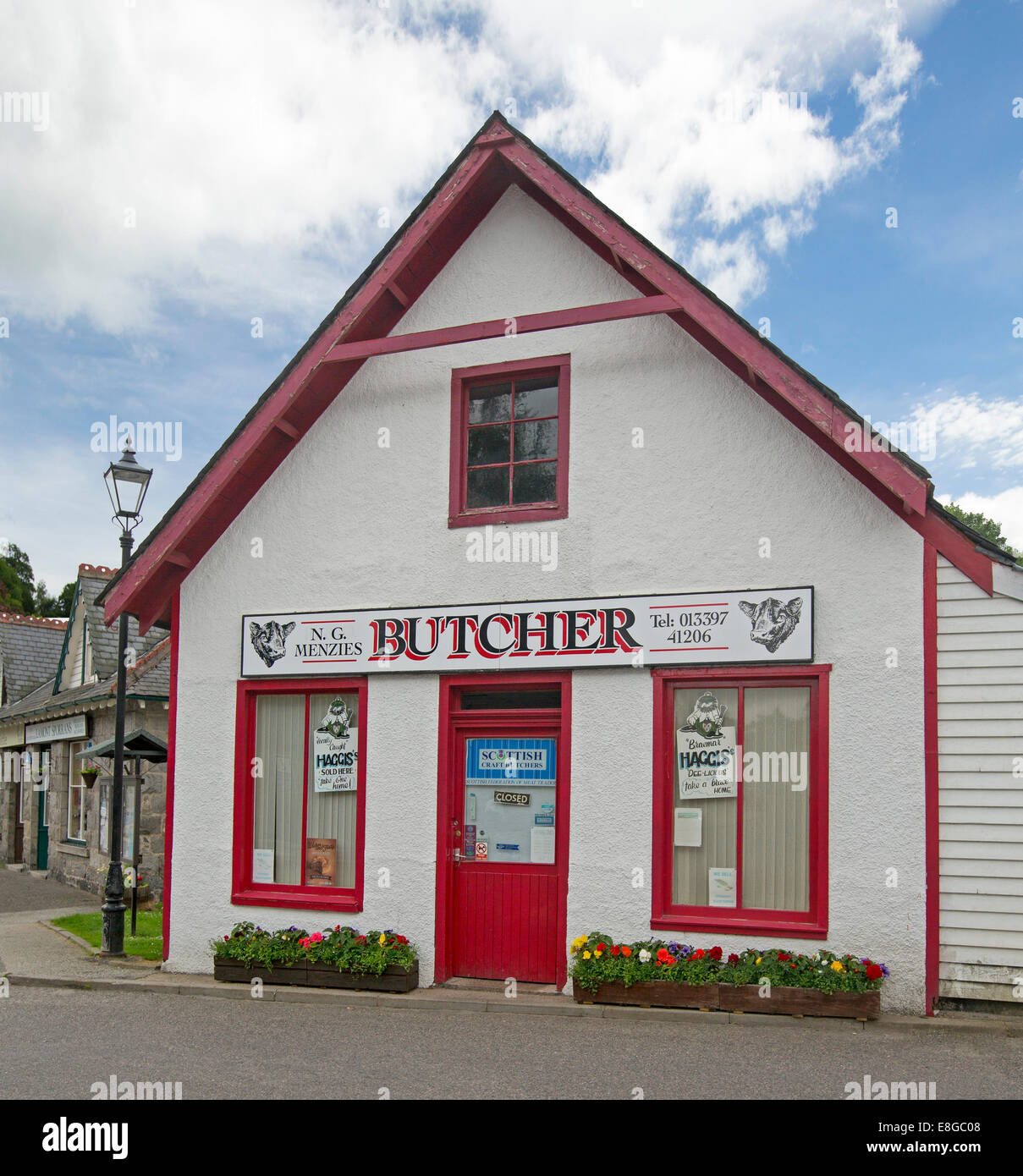 Red and white painted butcher's shop, with window boxes and flowers, in ...