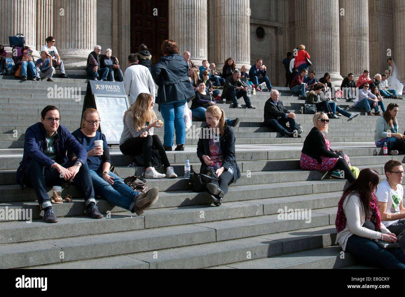 People sitting on the west front steps of St. Paul`s Cathedral, London ...