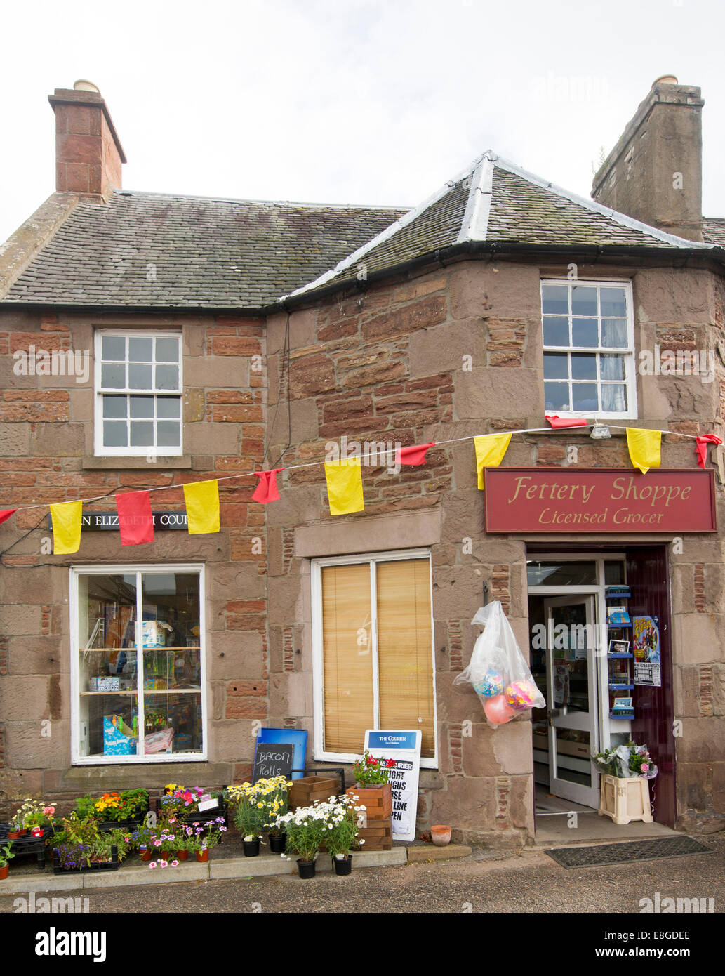 Small old fashioned general store with pots of colourful plants on ...