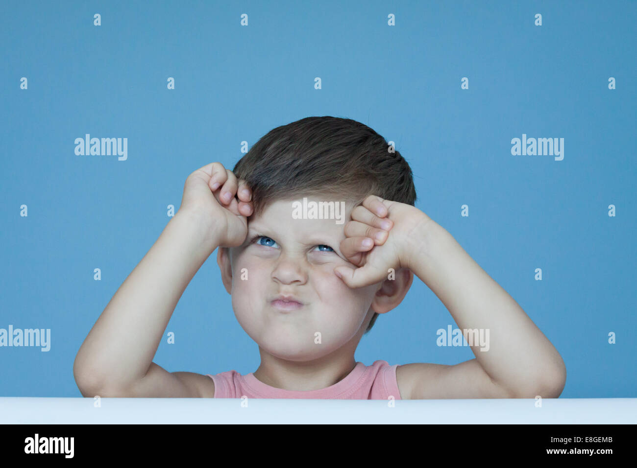 Three years old young boy holding hands on face and express irritation ...