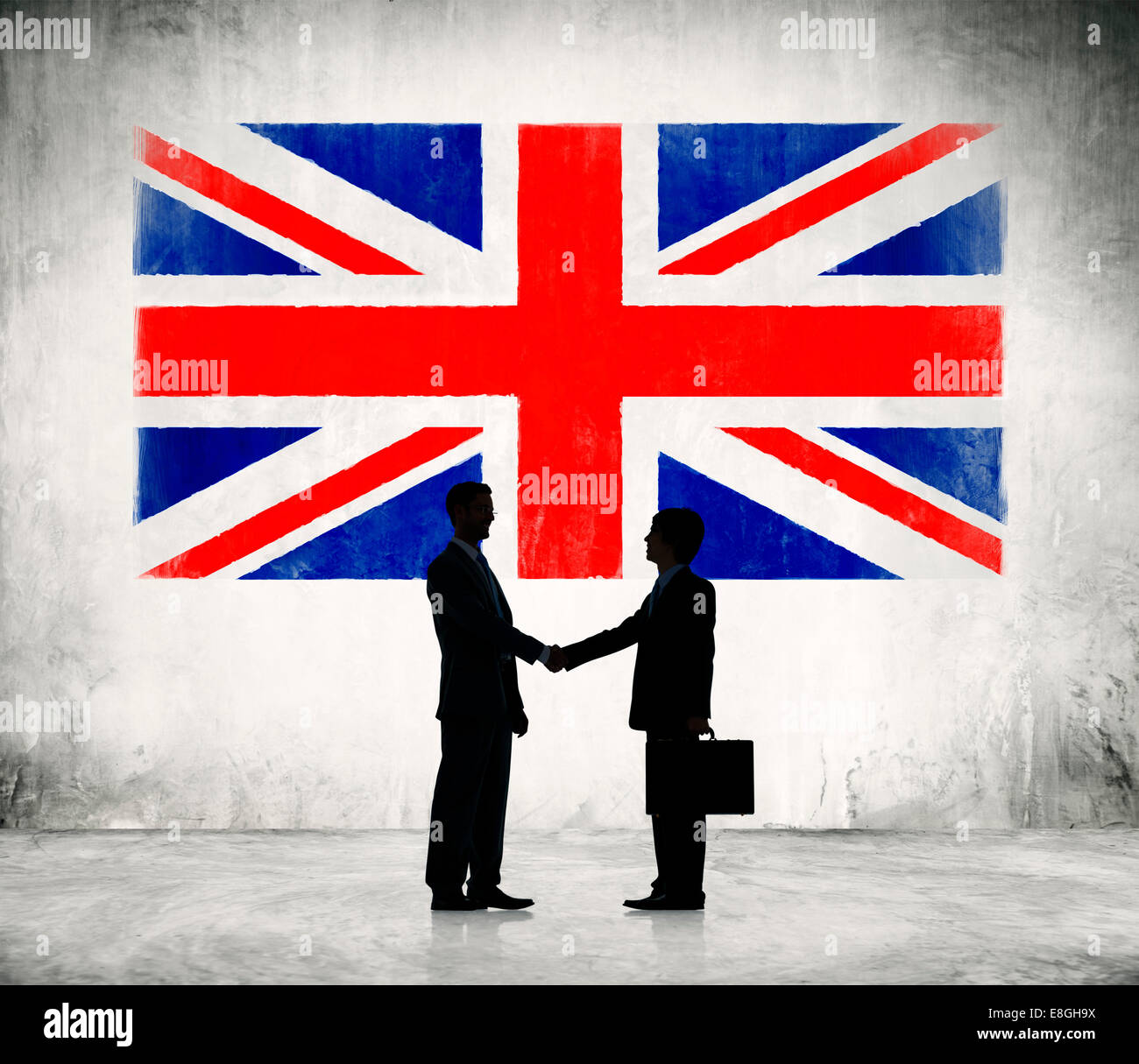 Two business men shaking hands infront of the flag of United Kingdom ...