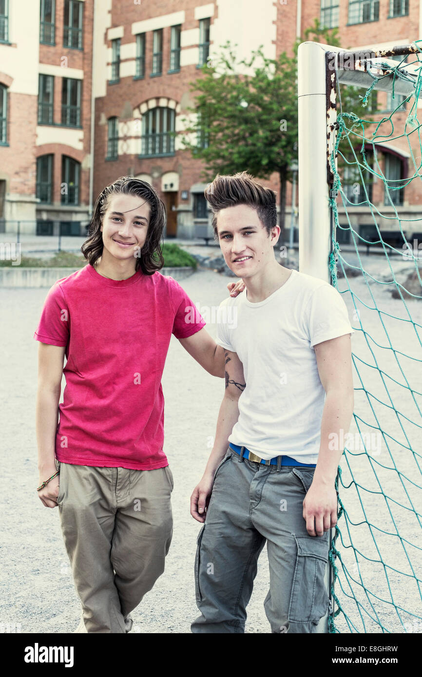 Portrait of confident male high school friends standing by soccer net ...