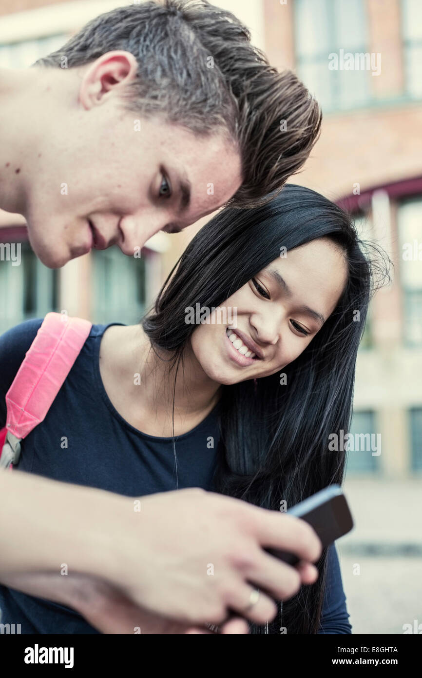 High school students reading text message on mobile phone in schoolyard ...