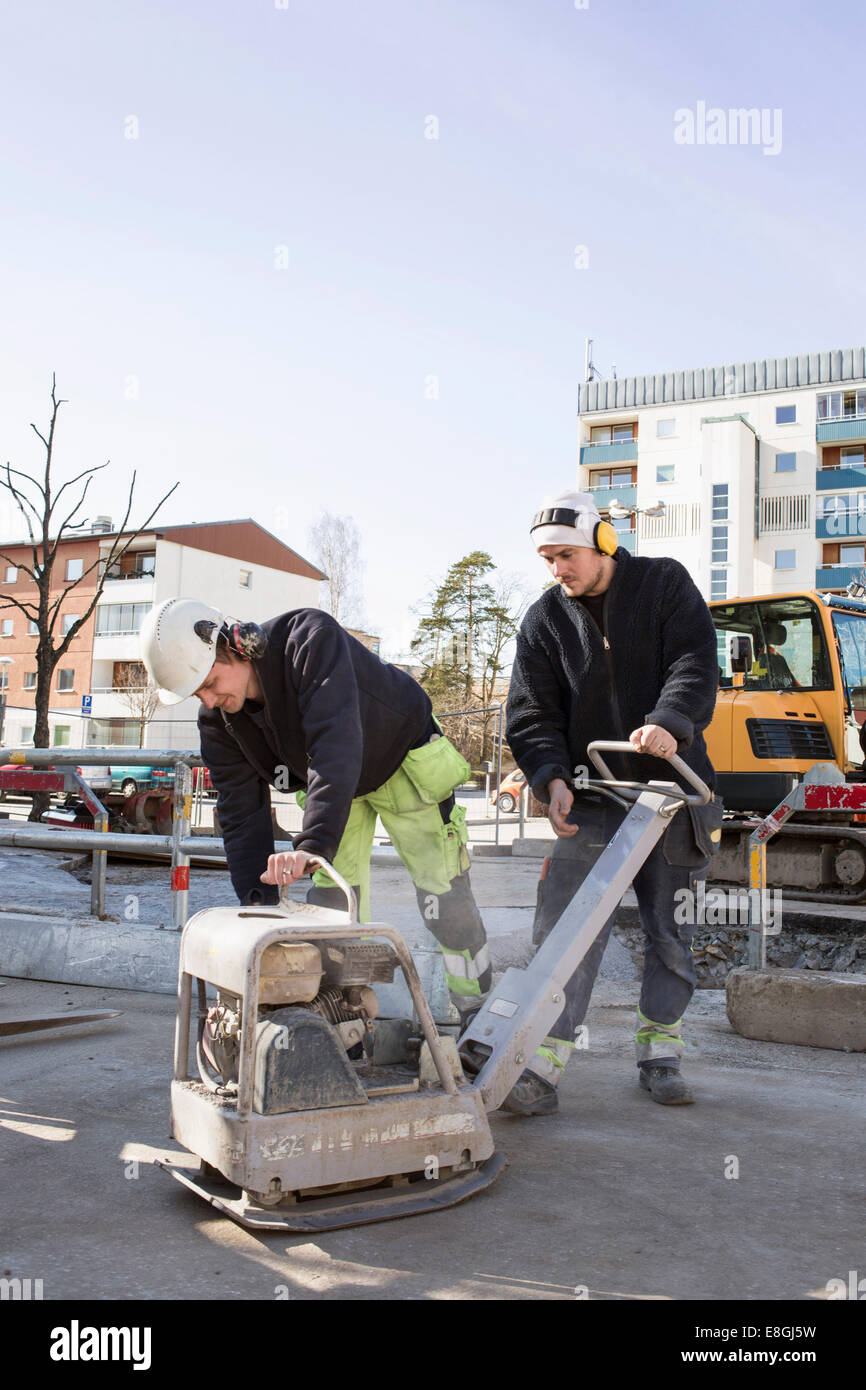 Workers operating machinery at construction site Stock Photo - Alamy