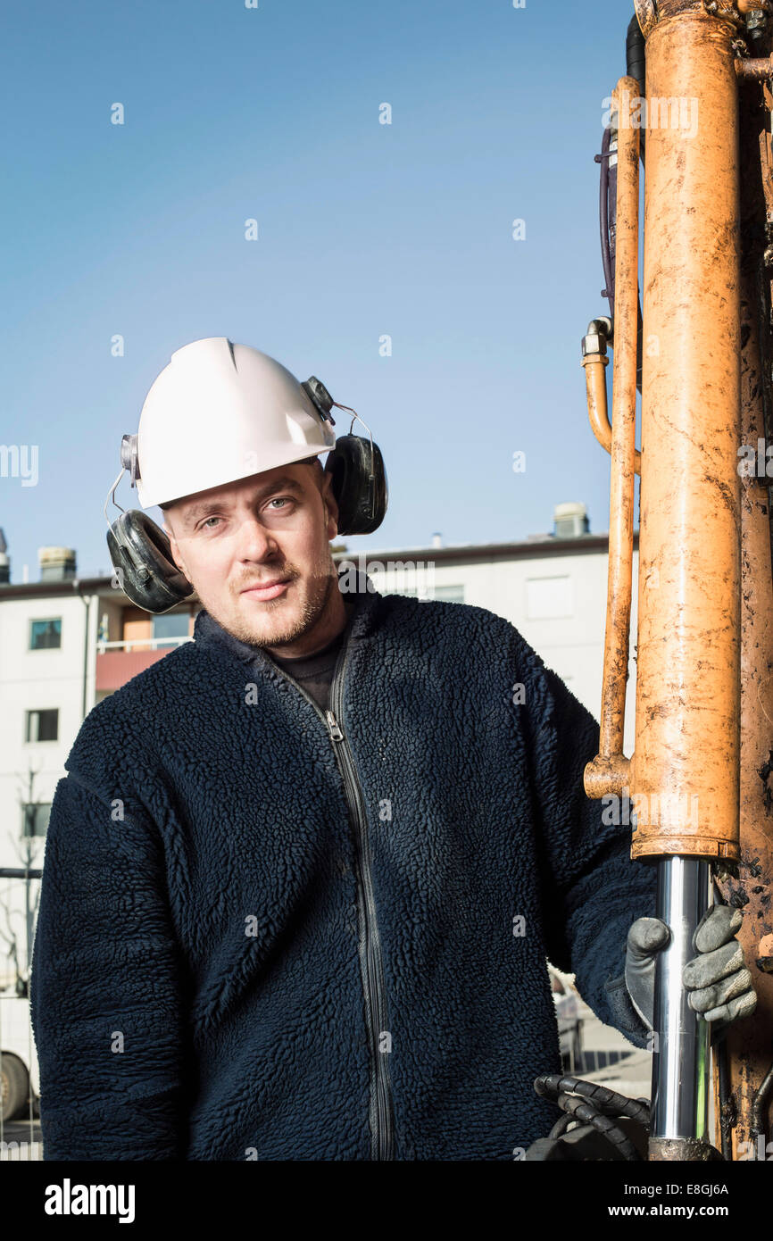 Portrait of confident construction worker holding rod of excavator ...
