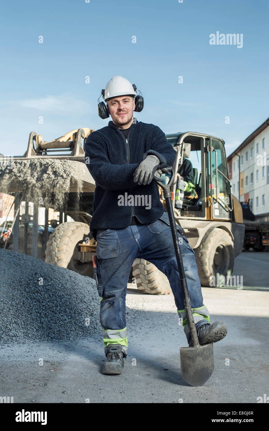 Full length portrait of confident worker standing at construction site ...