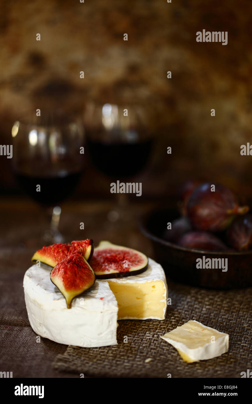 Close-Up of a wheel of Brie cheese with fresh figs and red wine on a ...