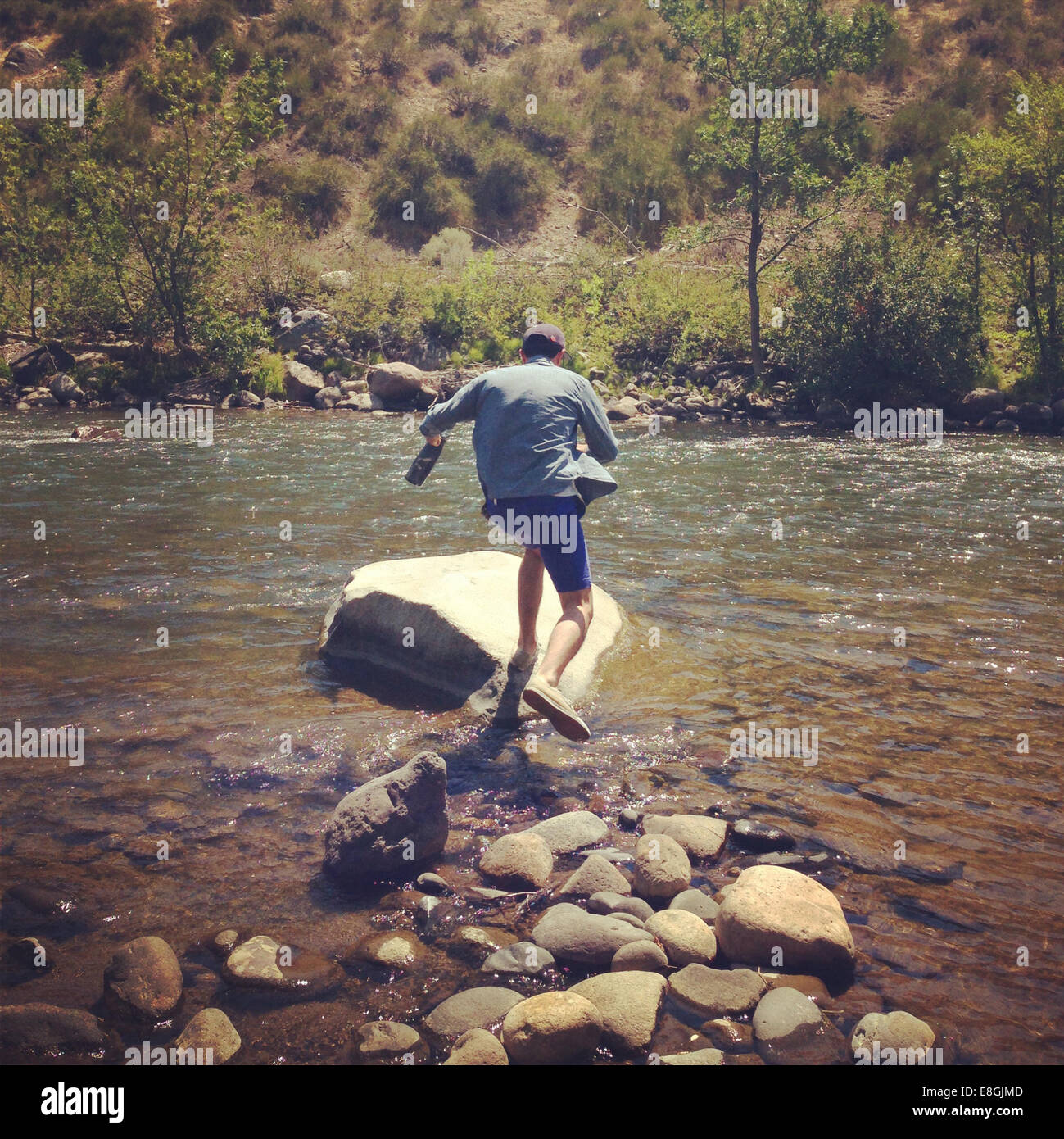 Man jumping across rocks in river Stock Photo - Alamy