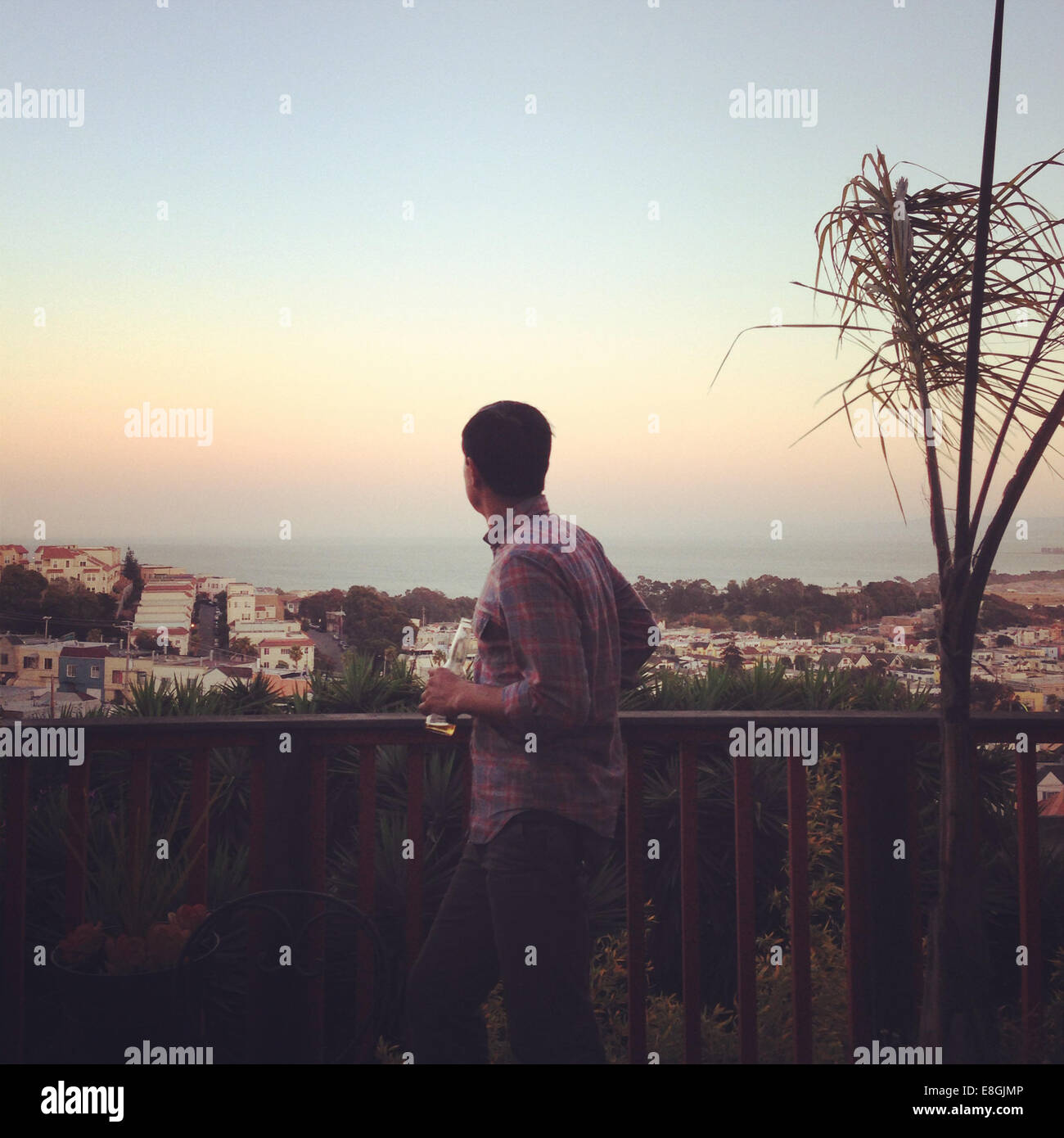 Man standing on a balcony looking at sunset hi-res stock photography ...