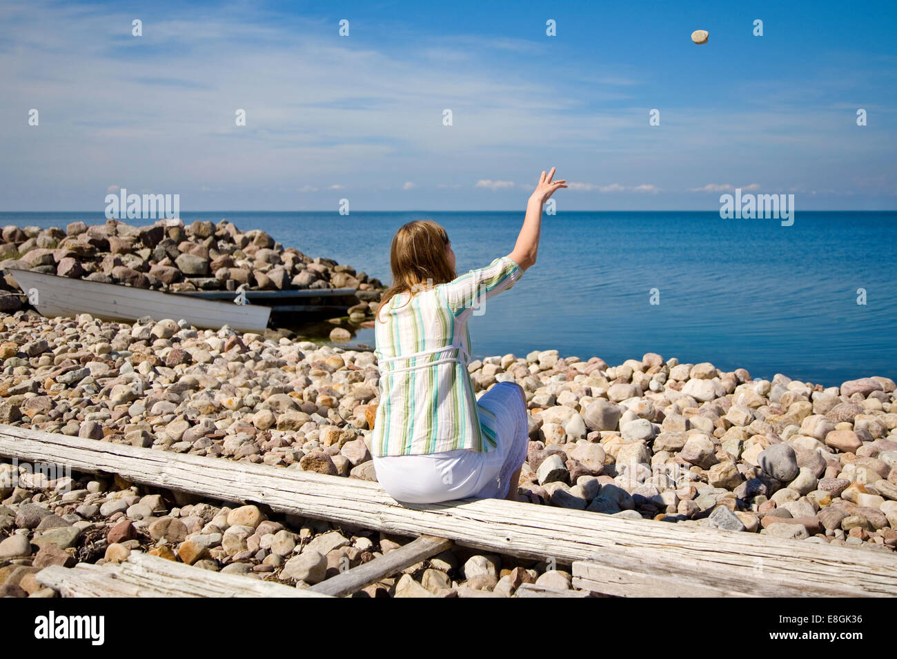 Woman throwing rock on rocky beach Stock Photo - Alamy