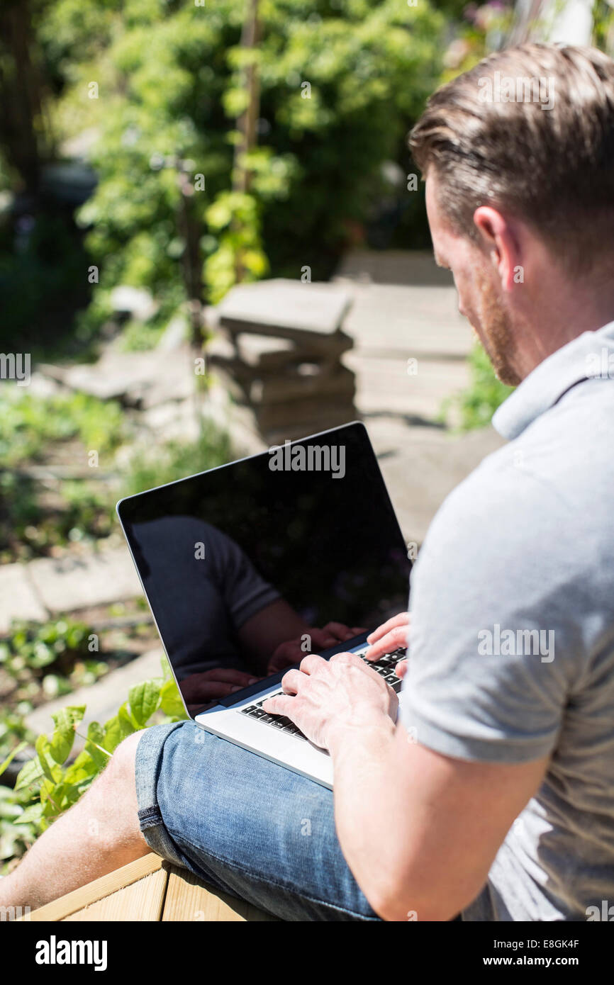 Side view of man using laptop on terrace Stock Photo - Alamy