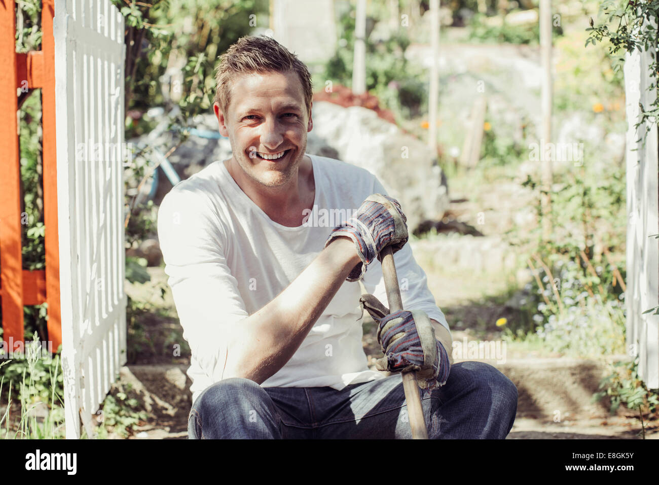 Portrait of happy man with gardening fork relaxing at yard Stock Photo ...