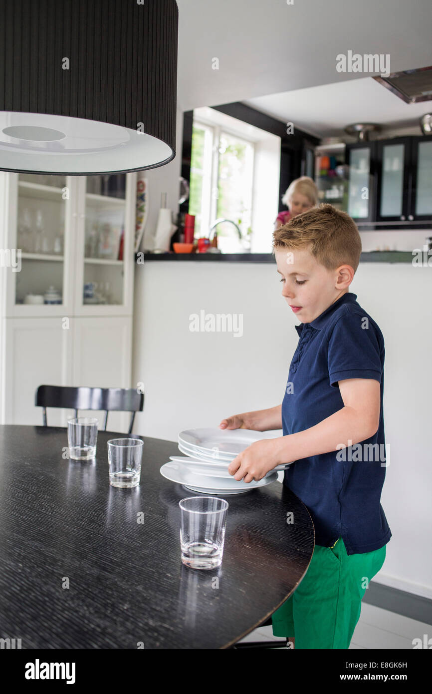 Boy arranging plates on dining table at home Stock Photo - Alamy