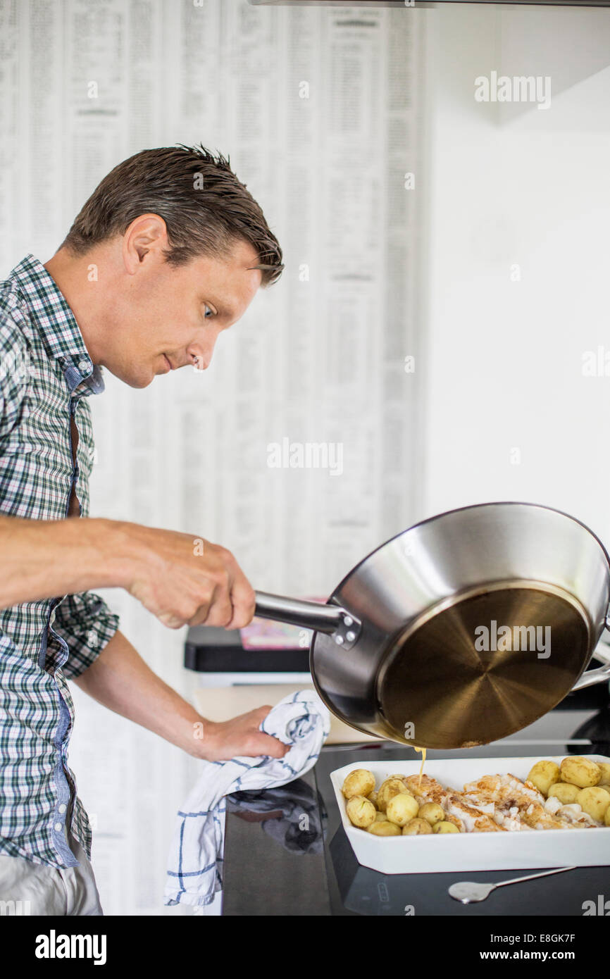 Side view of man preparing food in kitchen Stock Photo - Alamy