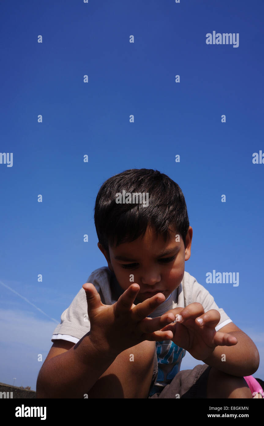 Portrait of a boy looking at his hand Stock Photo - Alamy