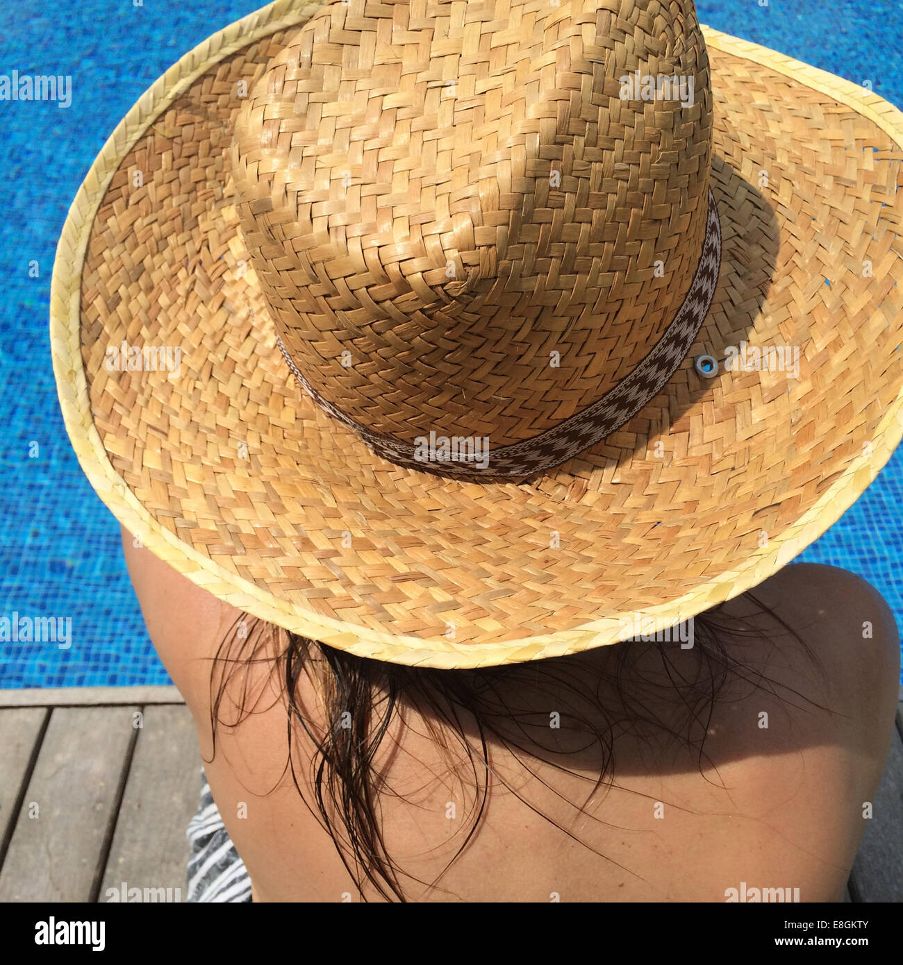 Woman in sun hat sitting by swimming pool Stock Photo - Alamy