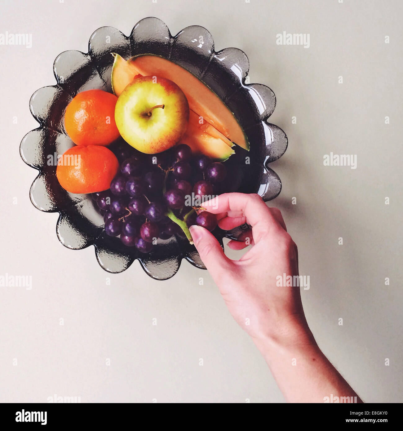 Woman's hand reaching for grapes in fruit bowl Stock Photo - Alamy