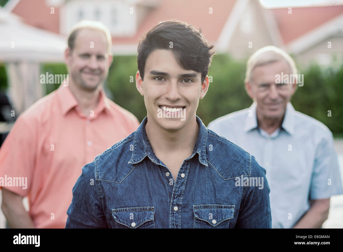 Portrait of confident young man with grandfather and father standing in ...