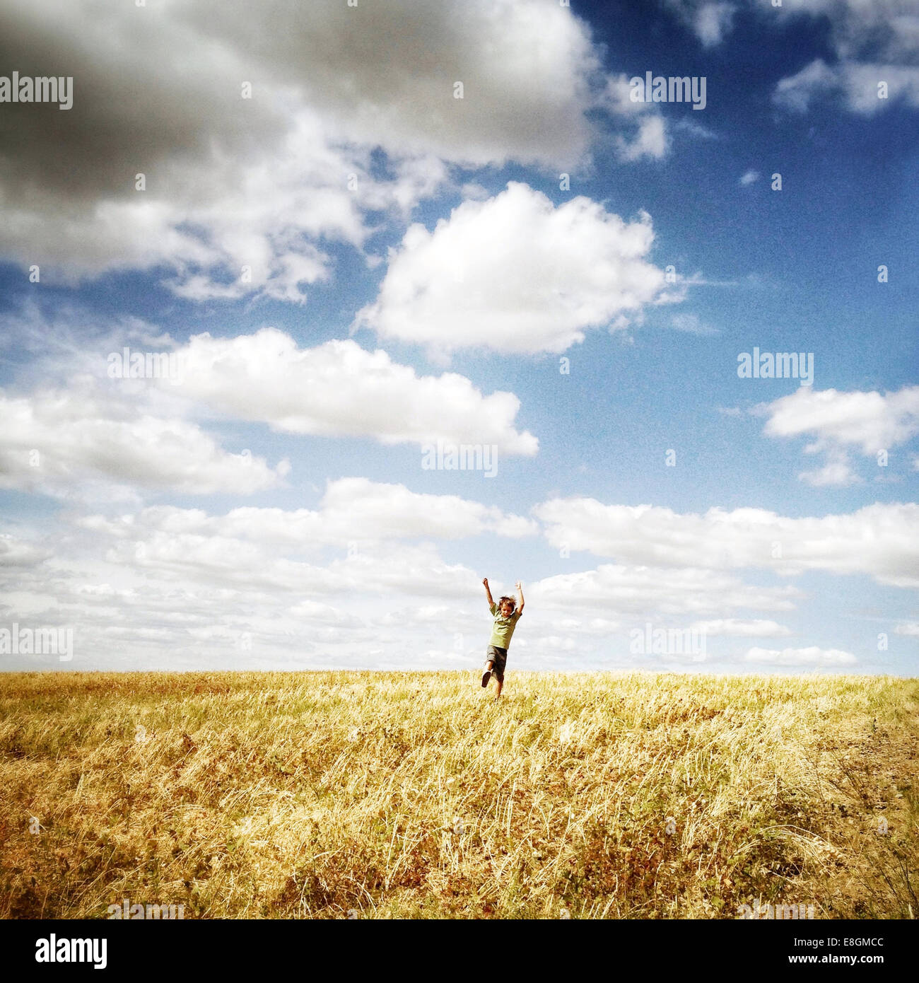 Happy boy running through a field with his arms in the air Stock Photo ...