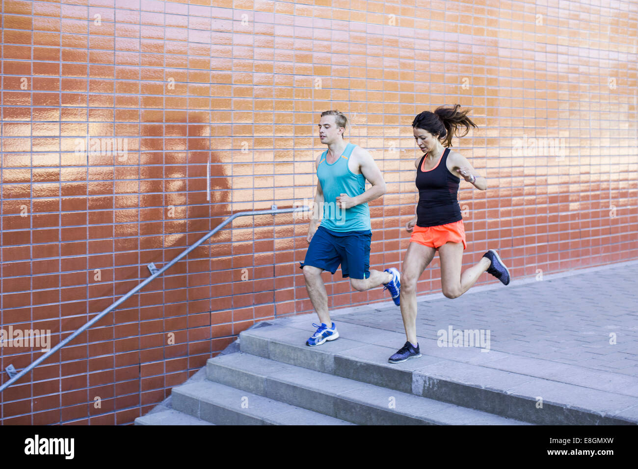 Full length of multi-ethnic couple running down steps outdoors Stock ...