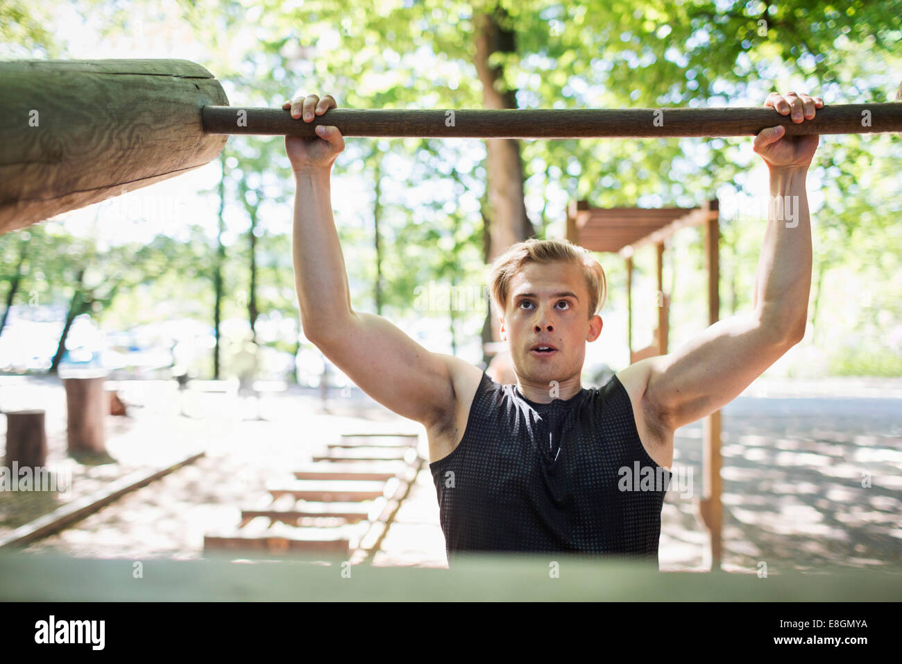 Determined man lifting wooden bar at outdoor health club Stock Photo ...