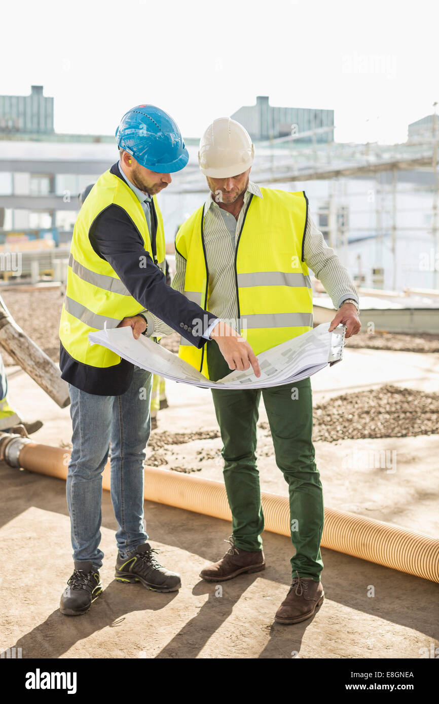 Engineers discussing over blueprint at construction site Stock Photo ...