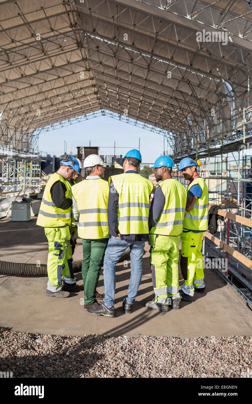 Rear view of construction workers standing at site Stock Photo - Alamy