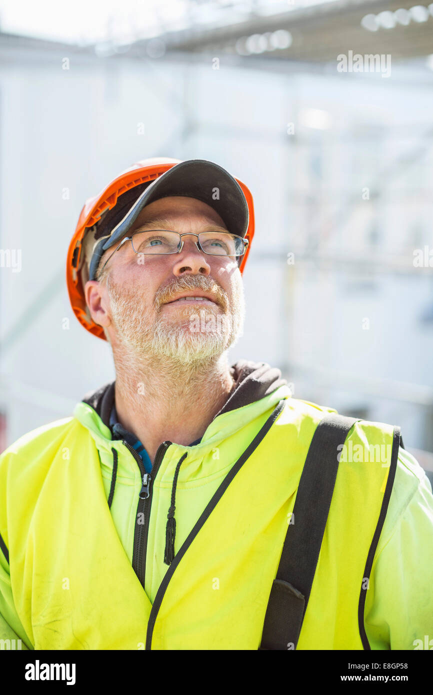 Construction worker looking up while standing at site Stock Photo - Alamy
