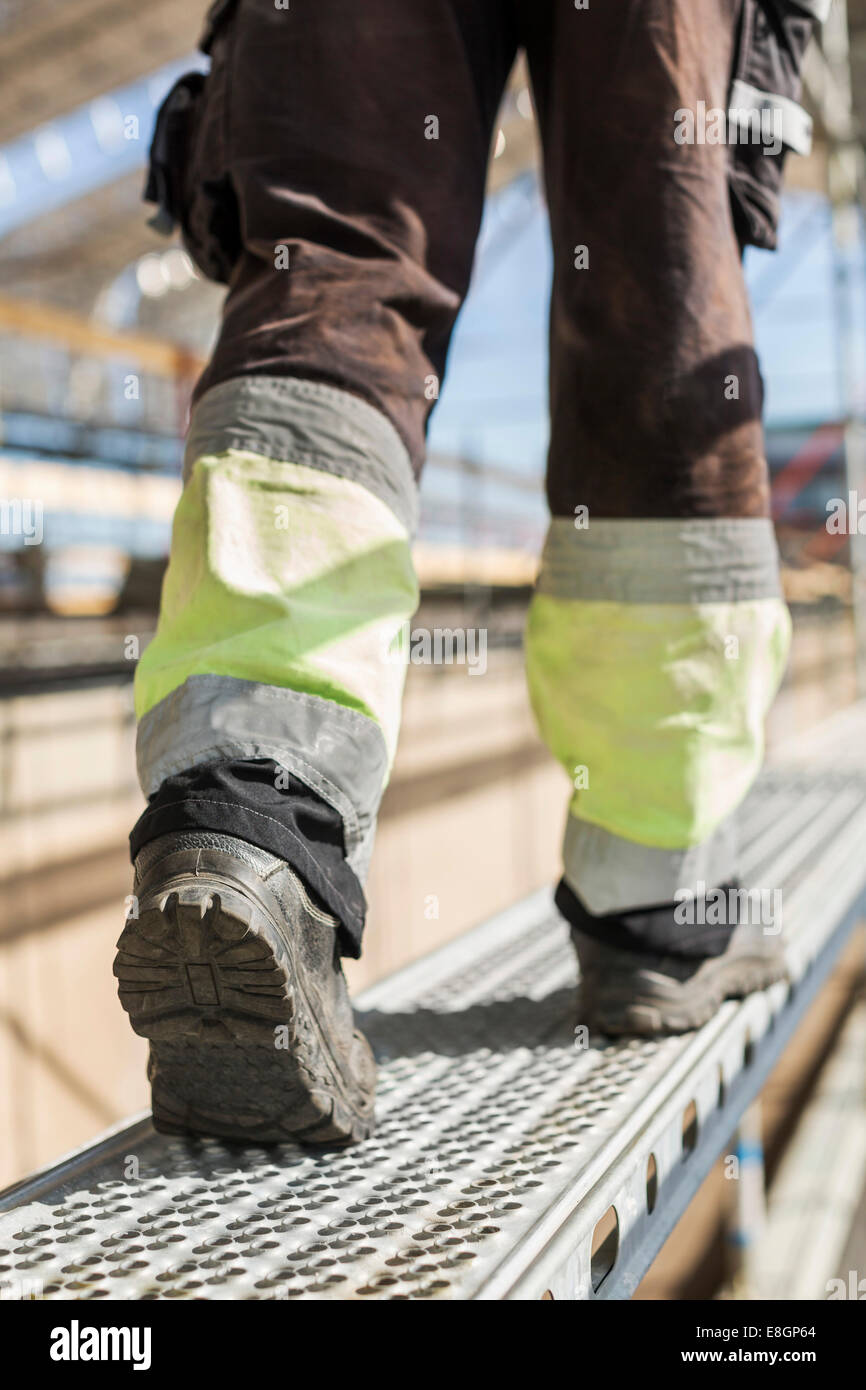 Low section rear view of worker walking on metal platform at ...