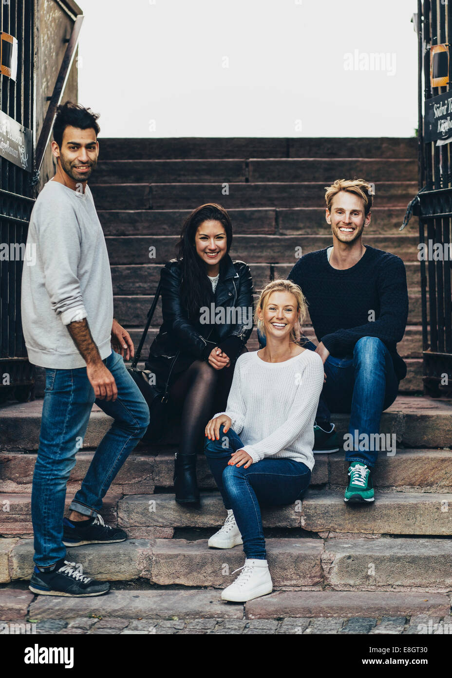 Portrait of four happy young friends standing over white background ...