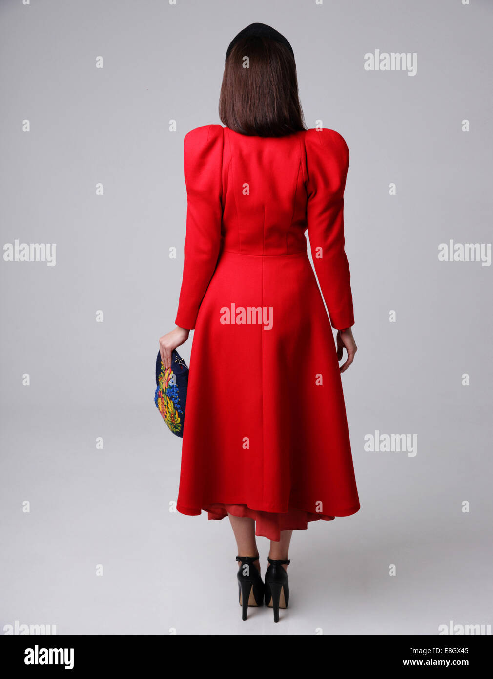 Back view portrait of a woman in red dress on gray background Stock ...