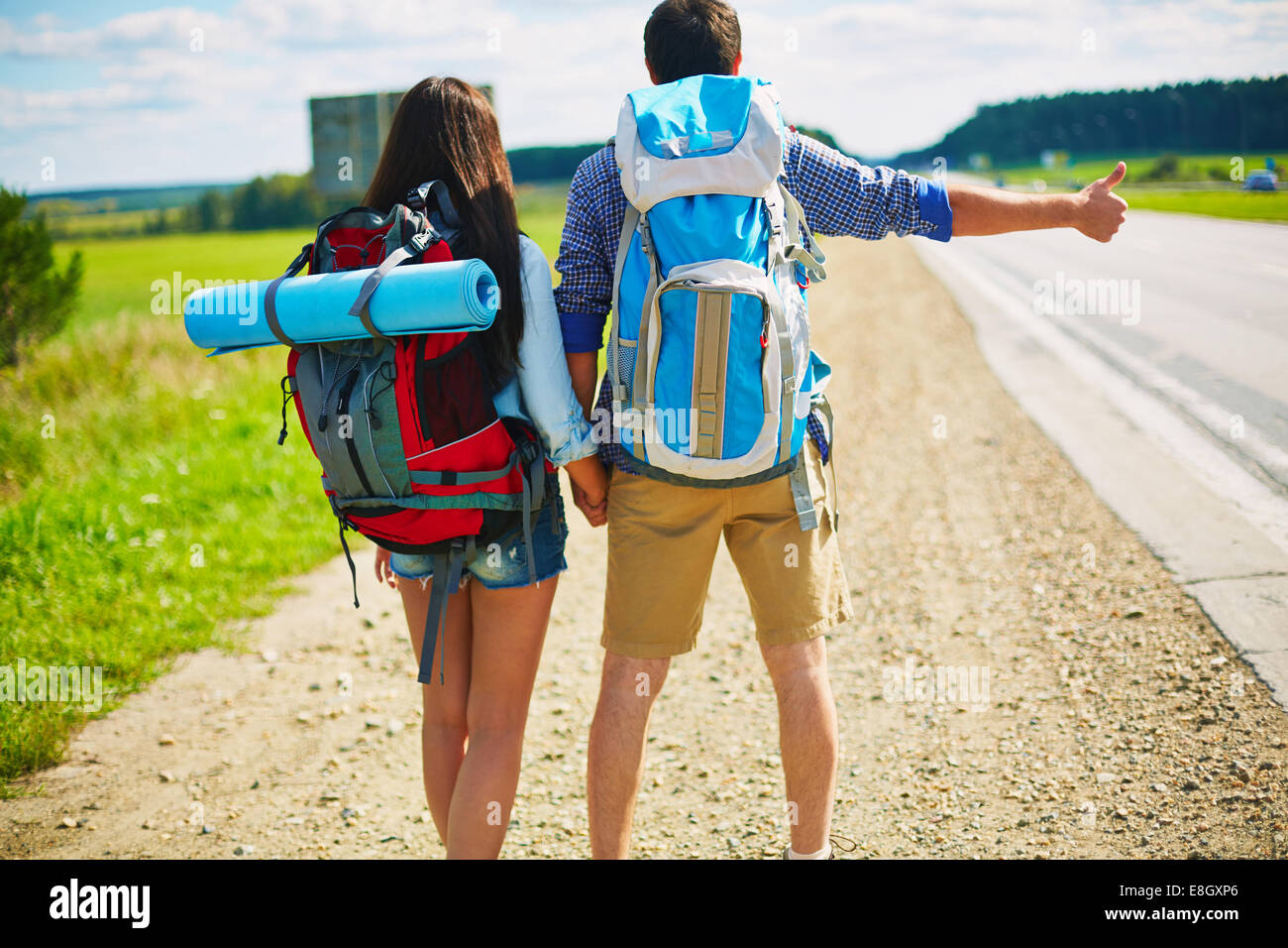 Couple of tourists hitching a ride Stock Photo - Alamy