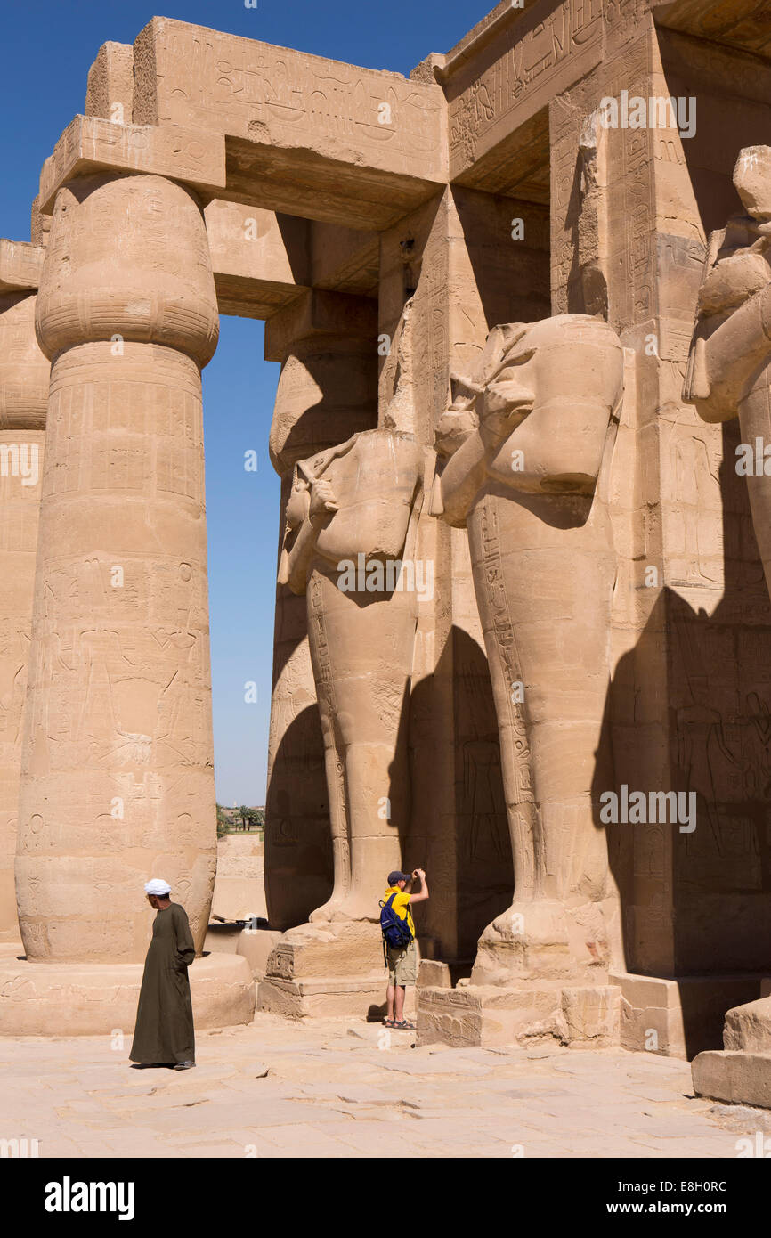 Egypt, Luxor, Ramesseum, tourist and local guide below headless statues ...