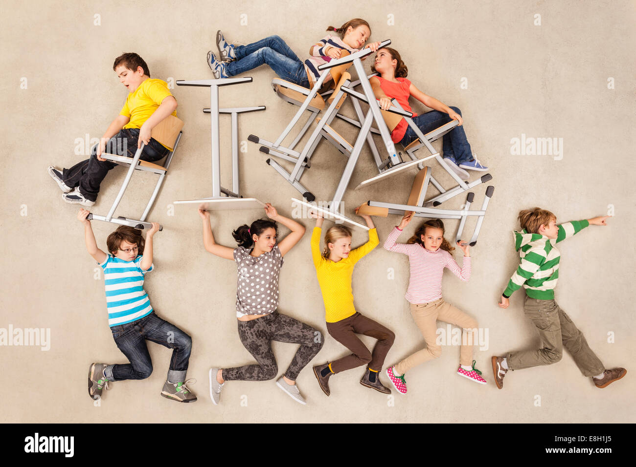 Children carrying pile of school chairs Stock Photo - Alamy