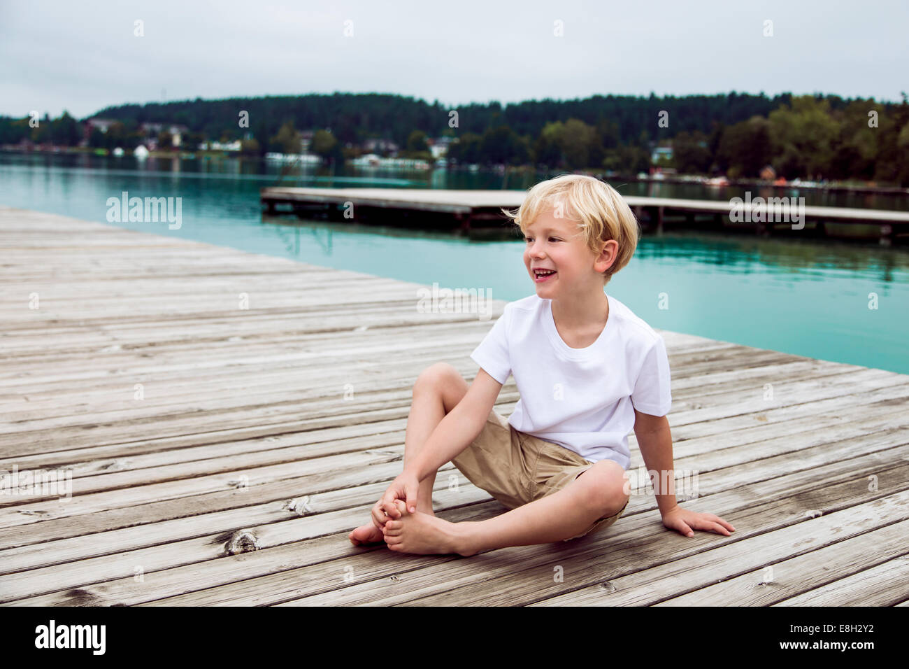 Portrait of smiliing little boy sitting on a jetty Stock Photo - Alamy