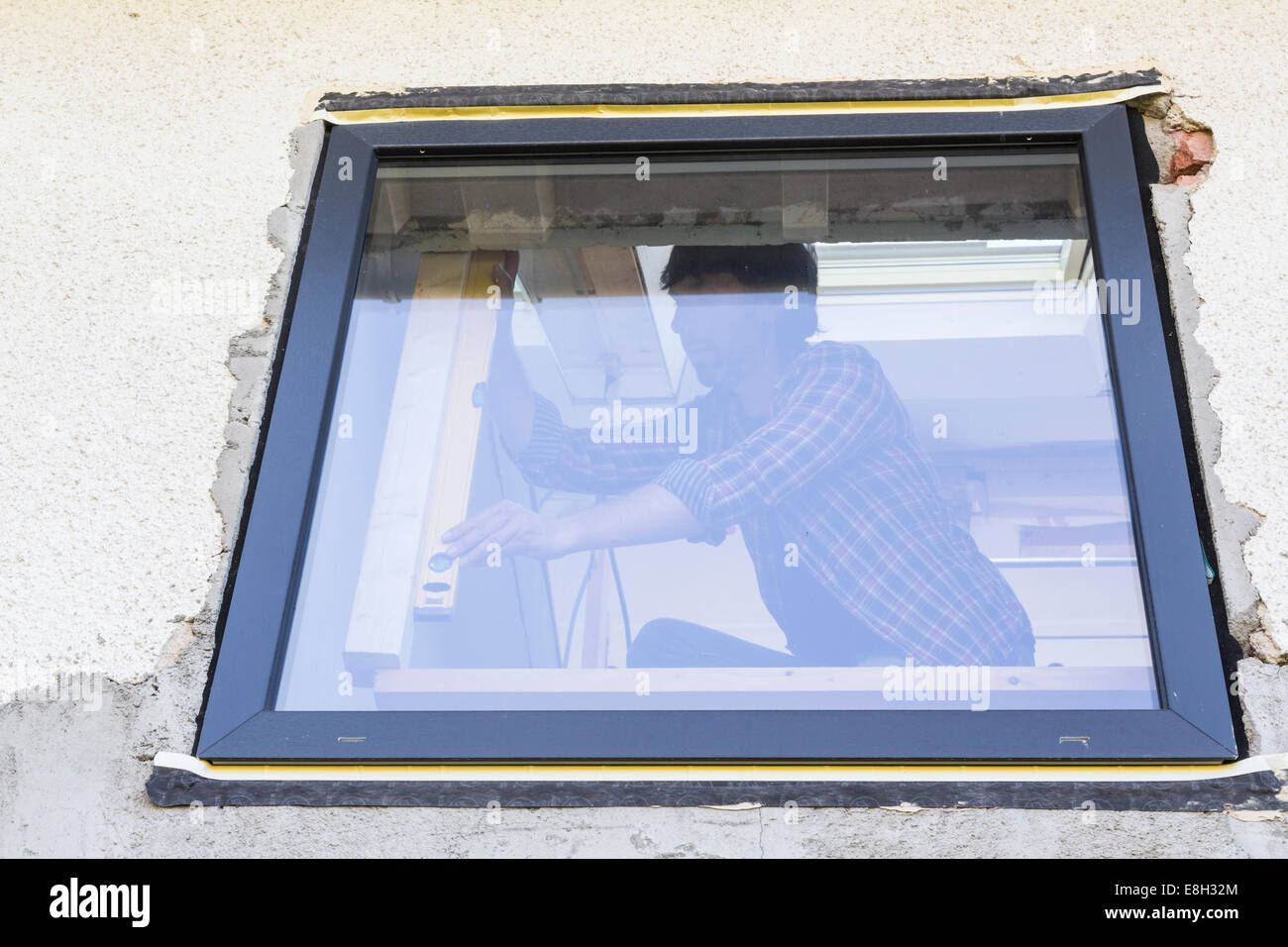 Man with water level at window during house renovation Stock Photo - Alamy