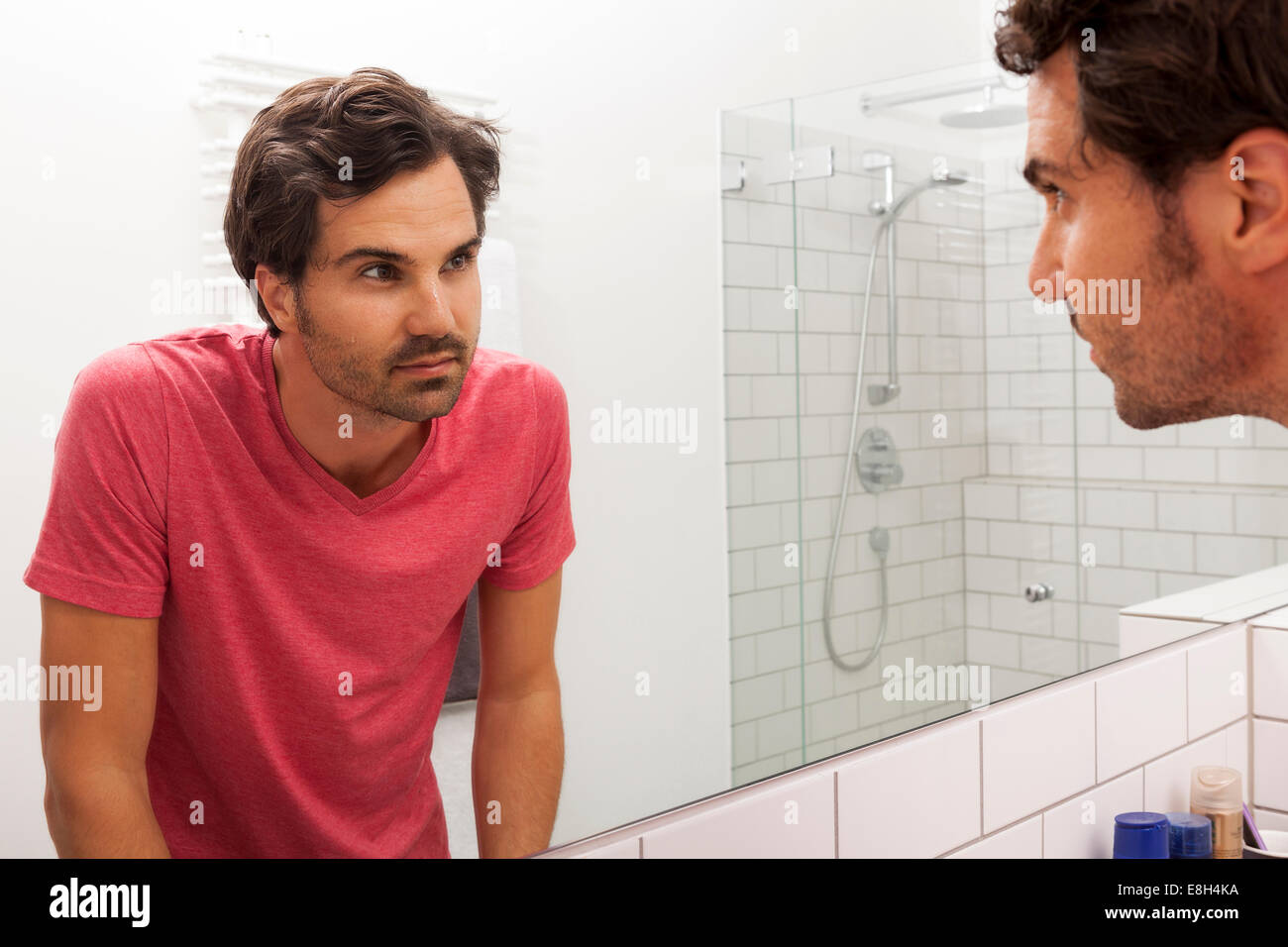 Mirror image of young man watching himself Stock Photo - Alamy