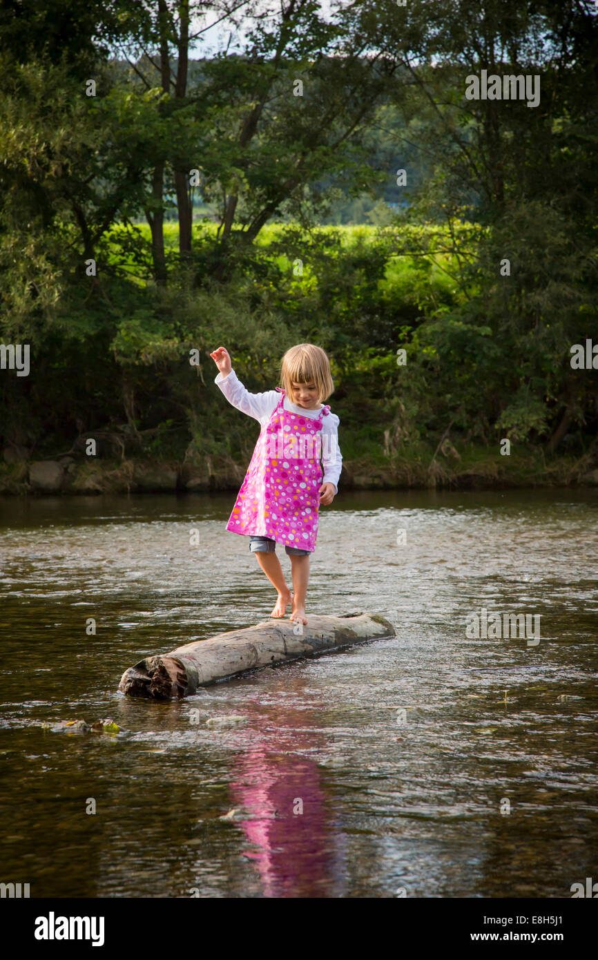 Little girl balancing on a rock in a river Stock Photo - Alamy