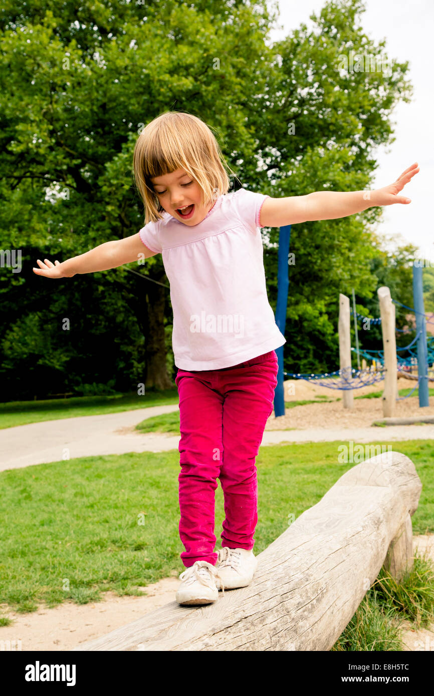 Little girl on playground balancing on log Stock Photo - Alamy