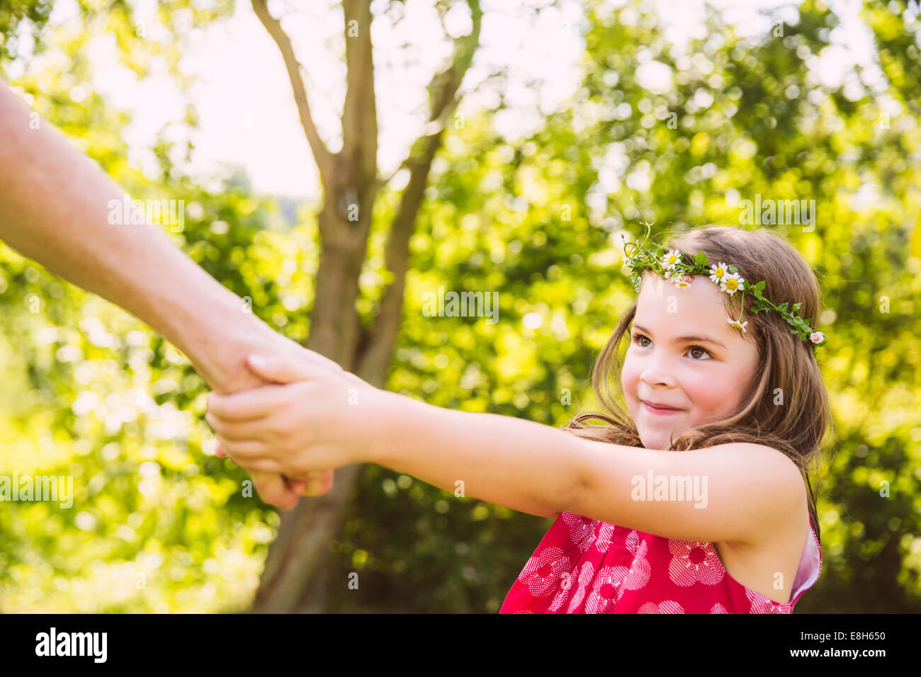 Girl pulling adult's arm in garden Stock Photo - Alamy