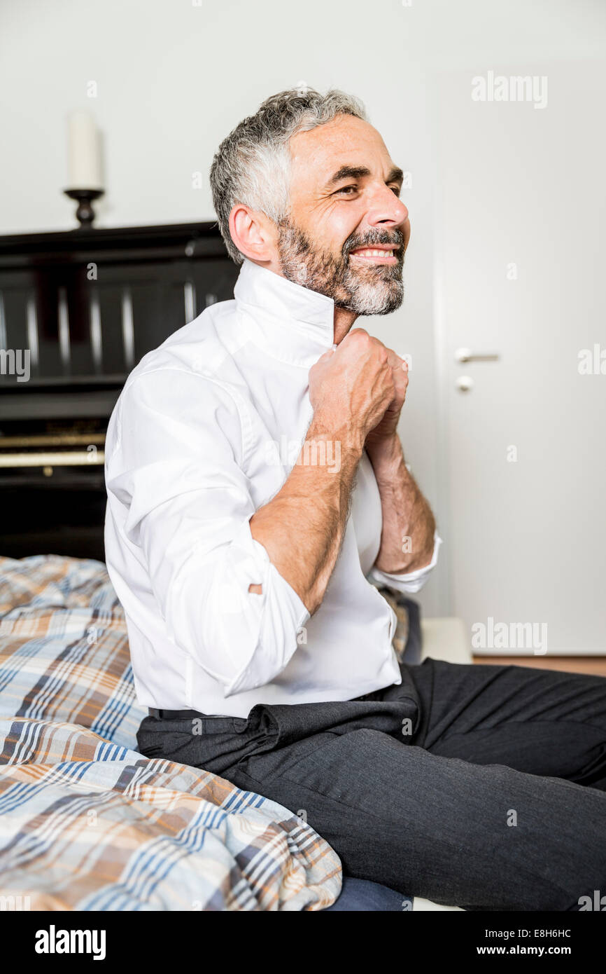 Portrait of smiling businessman binding tie in his bedroom Stock Photo ...