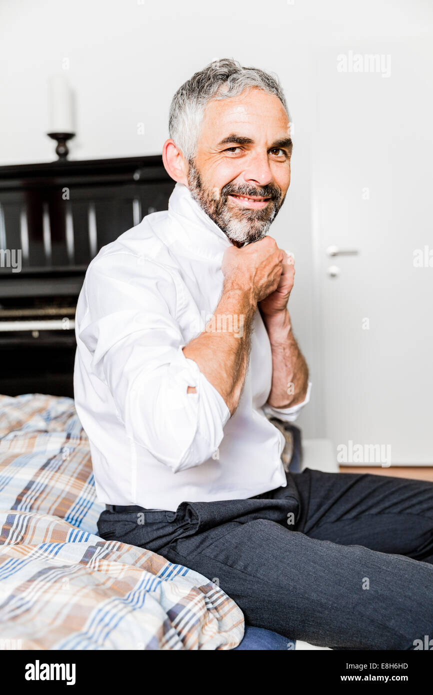 Portrait of smiling businessman binding tie in his bedroom Stock Photo ...
