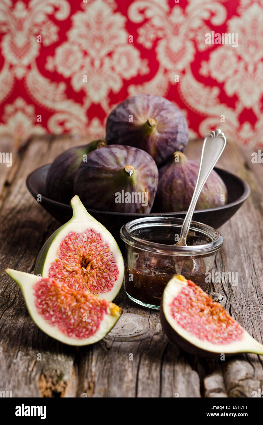 Sliced and whole figs and glass of fig jam on wooden table Stock Photo ...