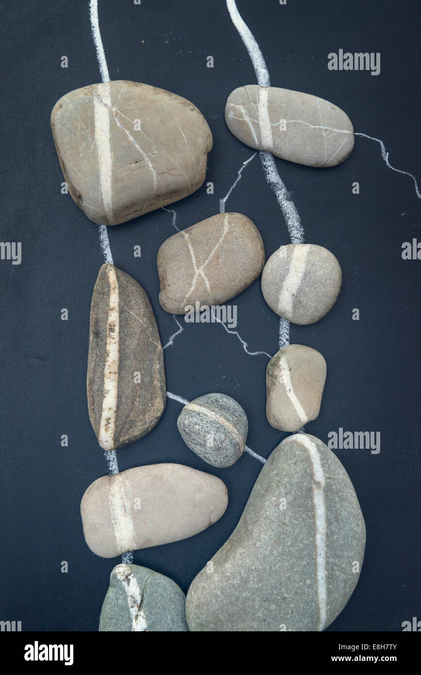 Pebbles with white line arranged on grey board Stock Photo - Alamy
