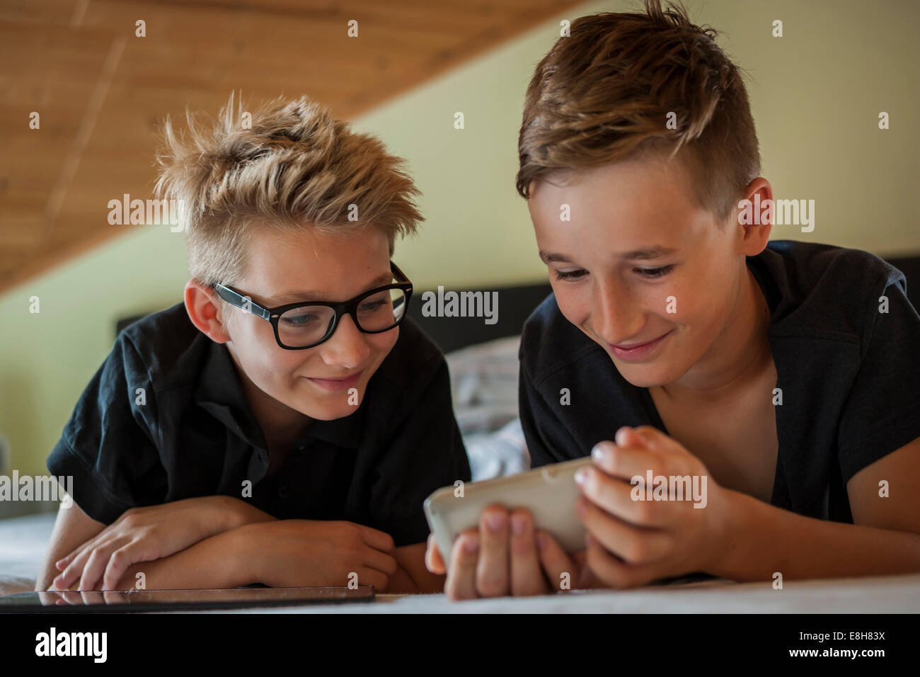 Portrait of two boys lying on bed using smartphone Stock Photo - Alamy