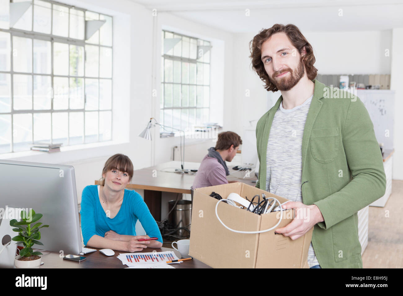 Portrait of young man with a cardboard box of power cables in a ...