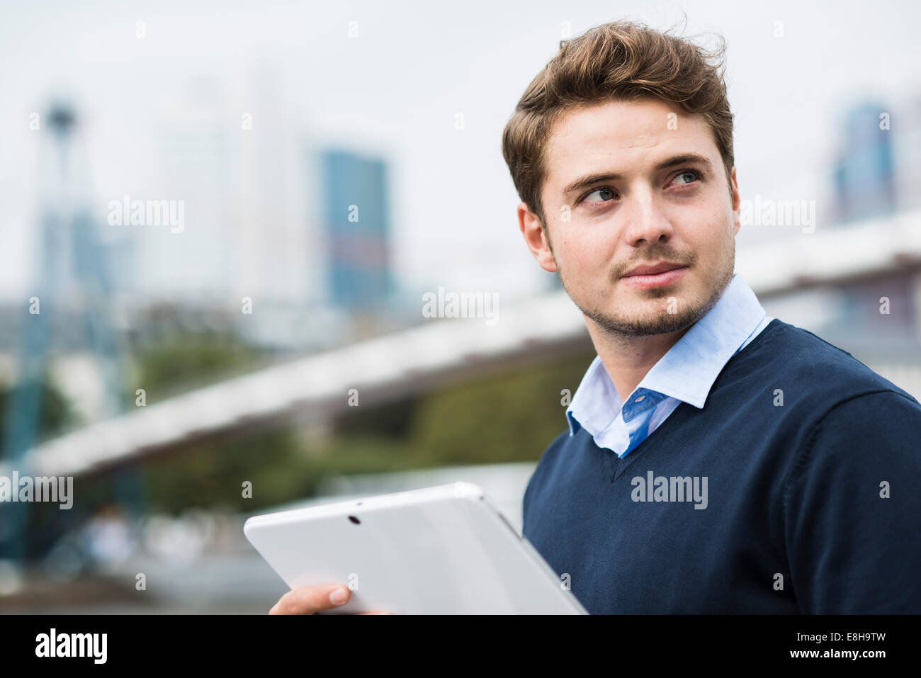 Germany, Hesse, Frankfurt, portrait of smiling young man with digital ...