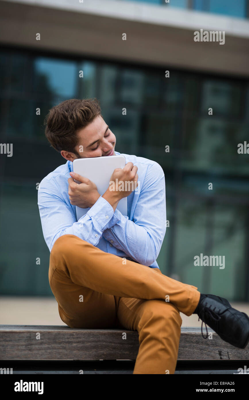 Germany, Hesse, Frankfurt, portrait of young man hugging his digital ...