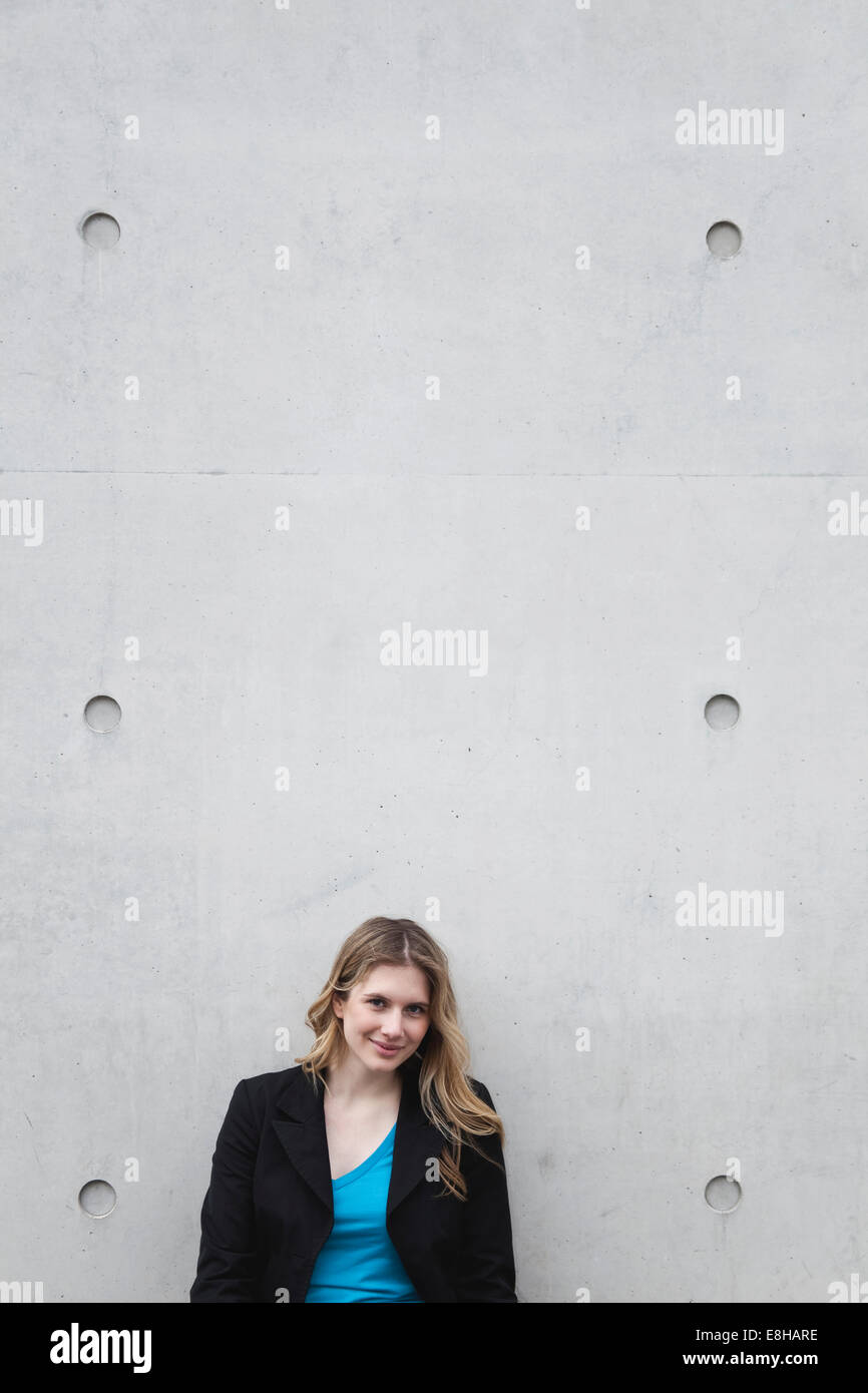 Germany, Berlin, Woman standing against wall, smiling, portrait Stock ...