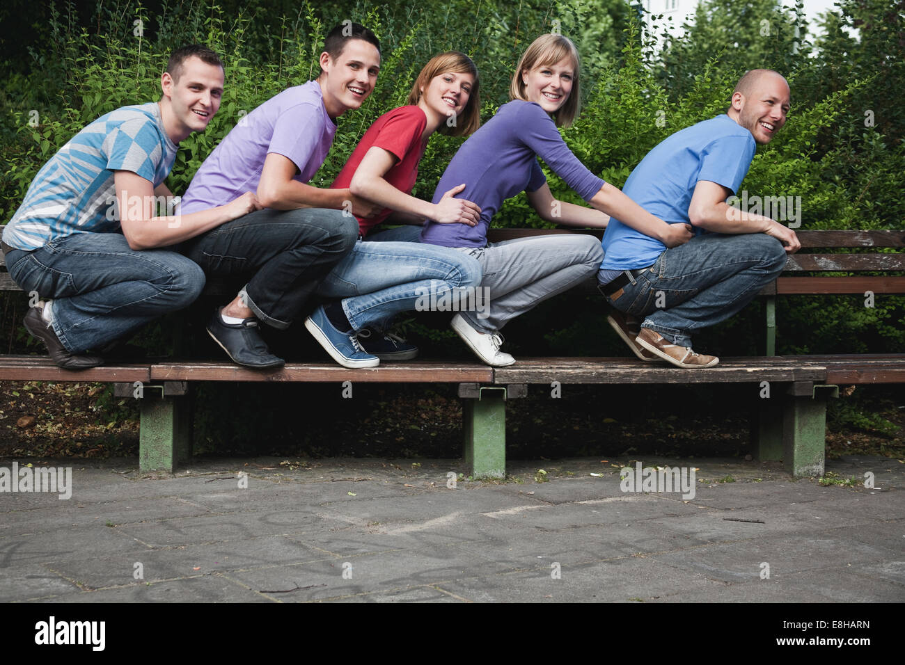 Germany, Berlin, Man and woman crouching in row and smiling, portrait ...